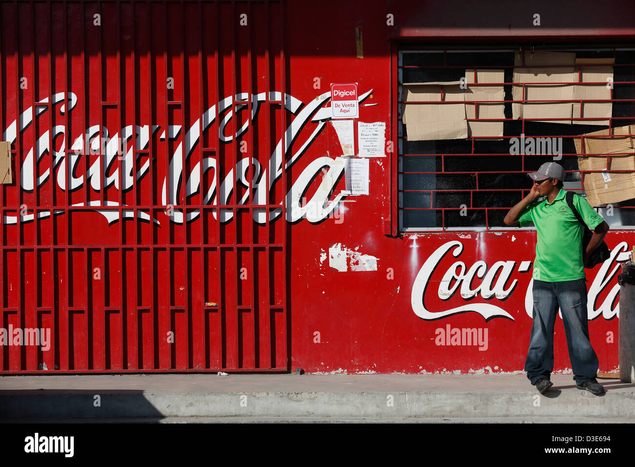 Man talking on cell phone in front of Coca Cola advertisement on a ...