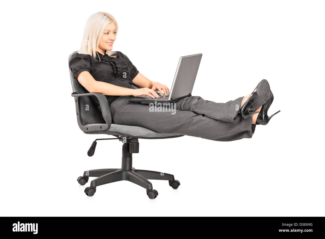 Young woman sitting on office chair with her legs up and working on a ...