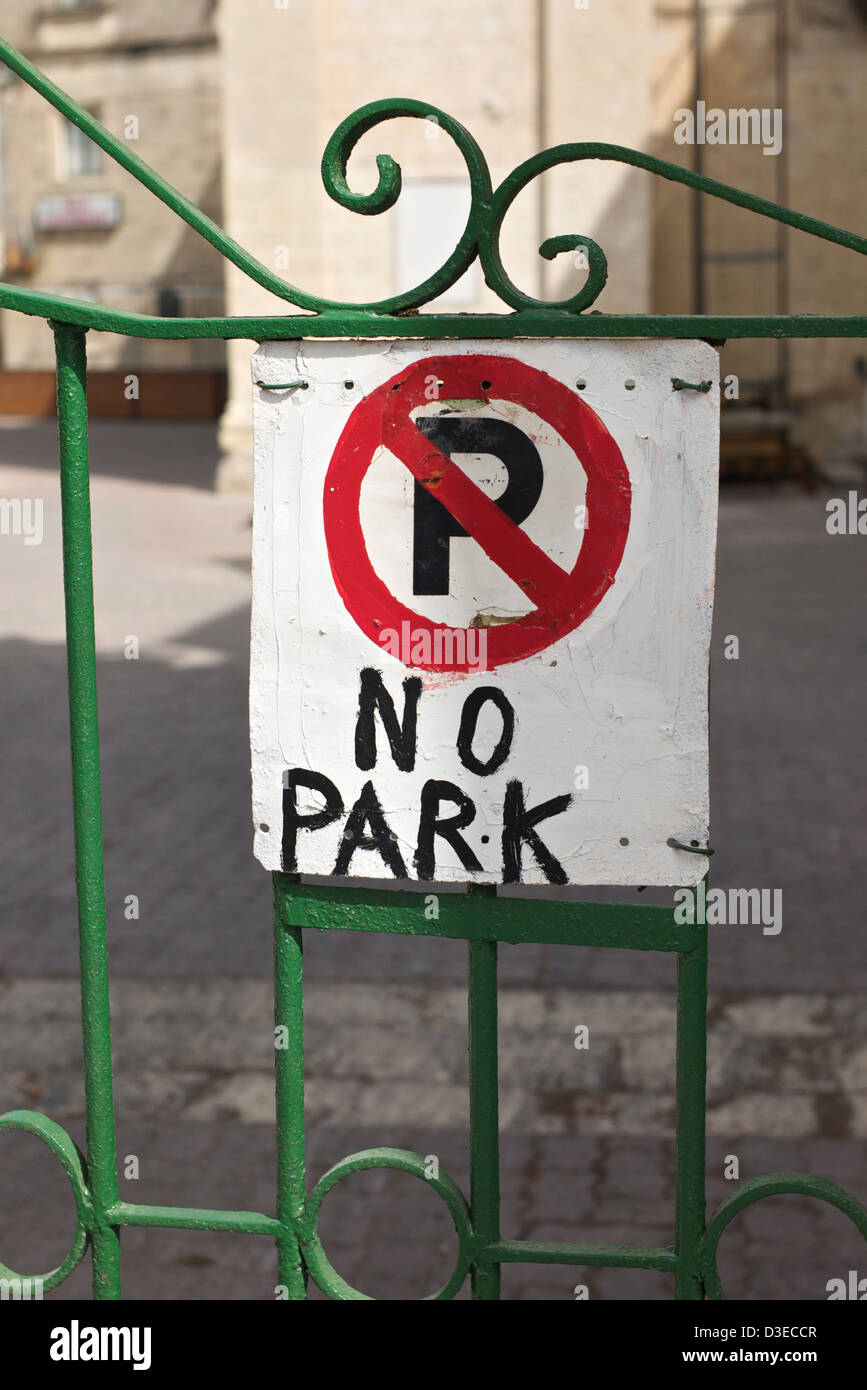 Hand written 'No Parking' sign attached to a green painted metal gate ...