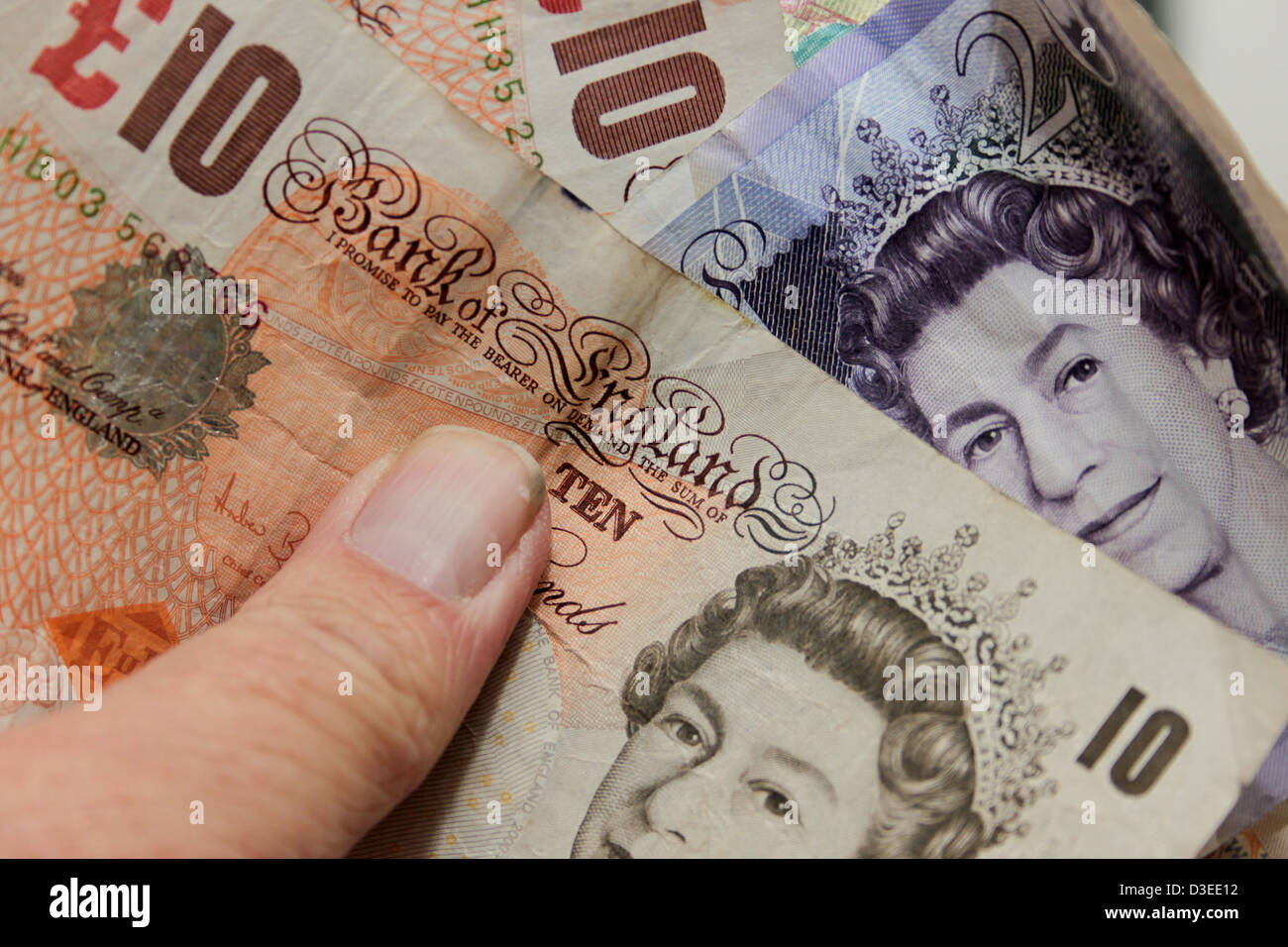 thumb holding british pound notes Stock Photo - Alamy