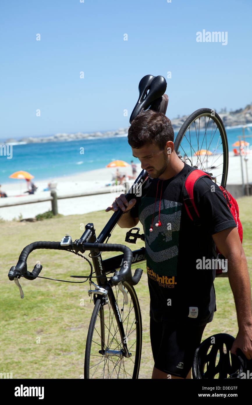 Man carrying Bike on shoulder on Camps Bay Beach - Cape Town Stock ...