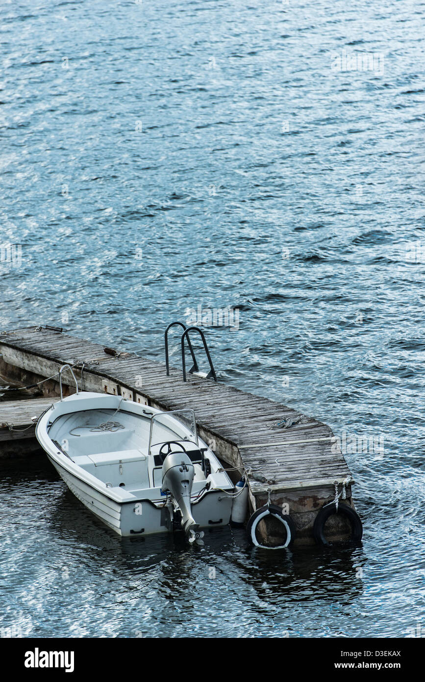 Empty marina with one motorboat tied to wooden jetty and a storm coming ...