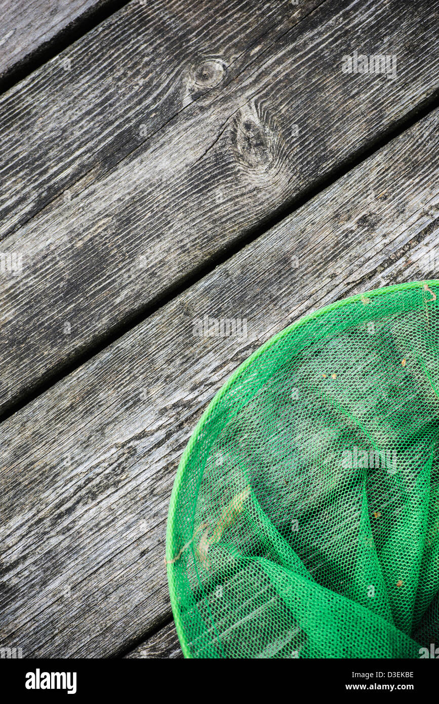 Closeup of green fishing net lying on weathered wooden deck of jetty ...