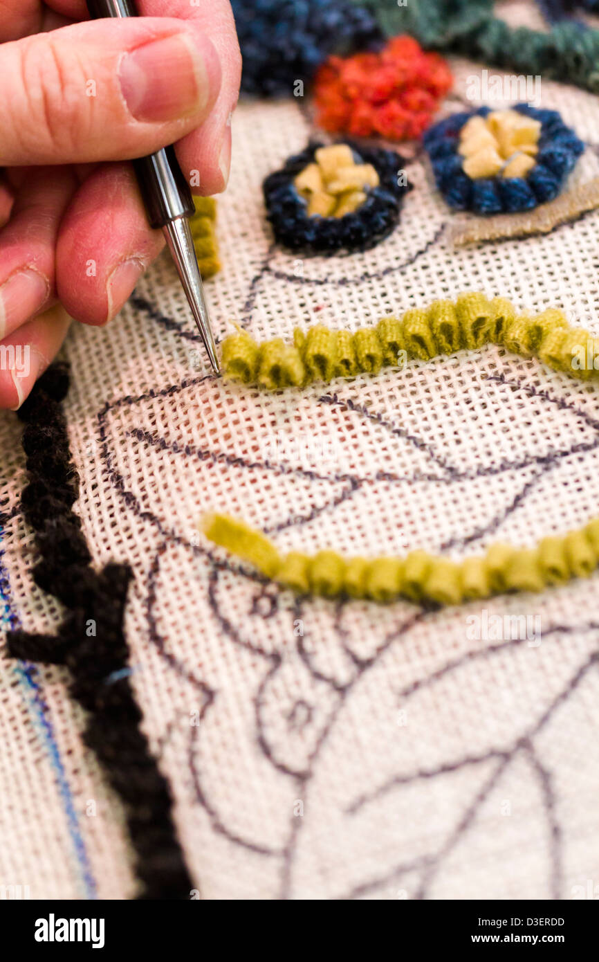 Hands work a hook in hug hooking craft Stock Photo - Alamy