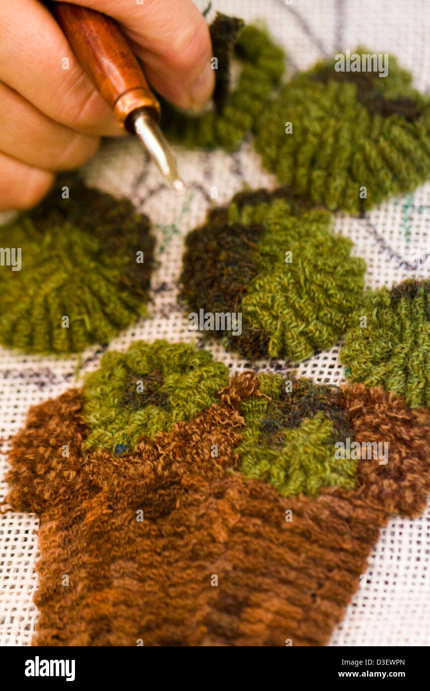 Hands work a hook in hug hooking craft Stock Photo - Alamy