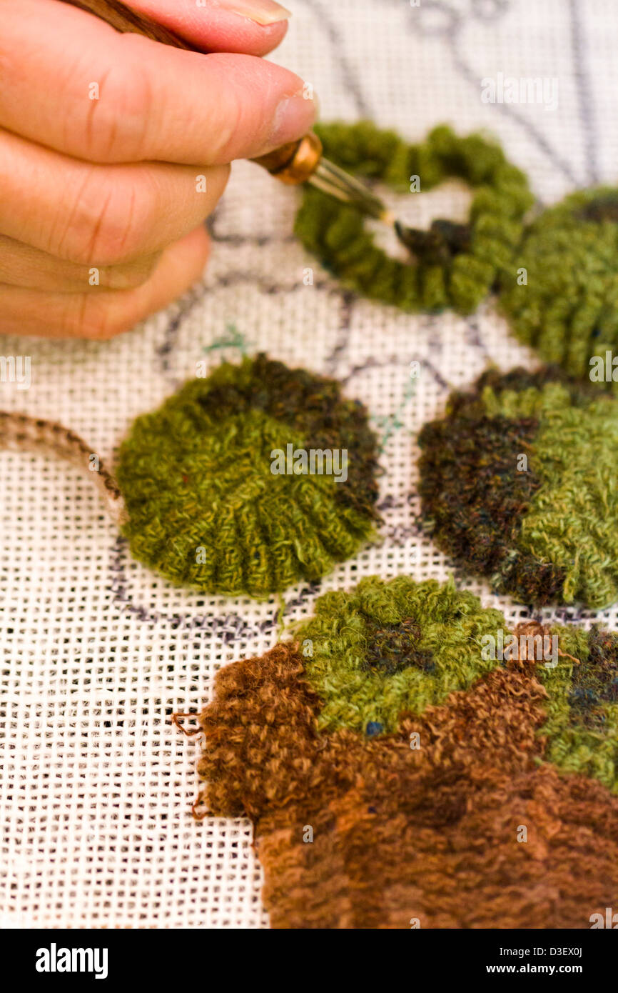 Hands work a hook in hug hooking craft Stock Photo - Alamy