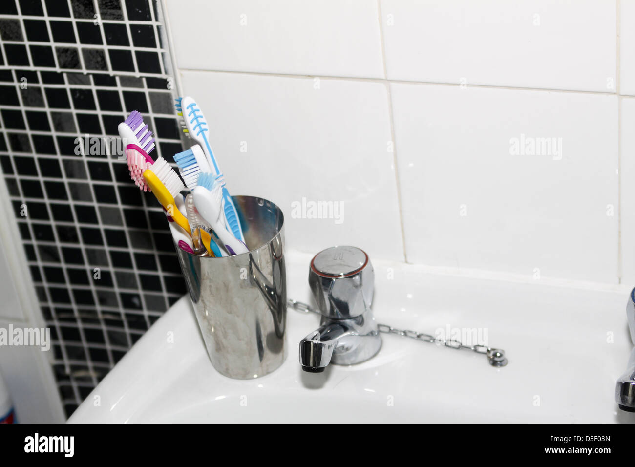 family toothbrushes in chrome holder on sink Stock Photo - Alamy