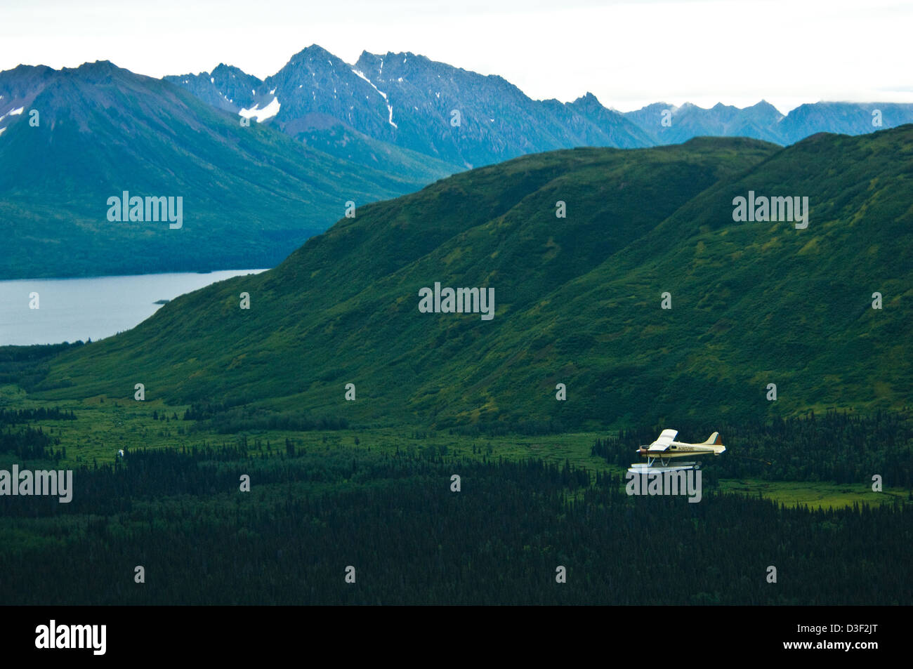 DeHavilland Beaver floatplane flying over mountains lakes and tundra ...