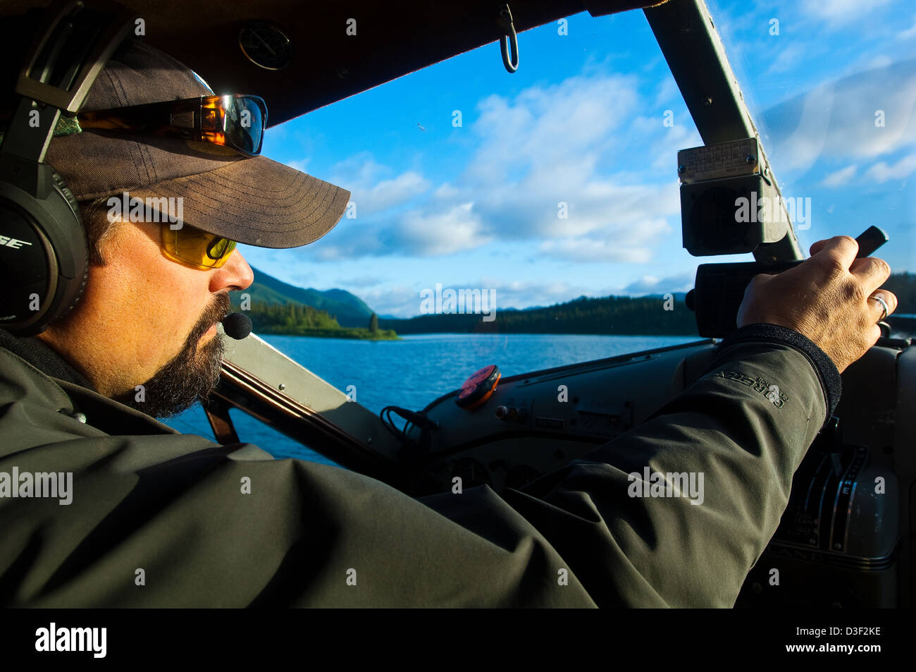 Pilot flying DeHavilland Beaver floatplane over forest and lakes, near ...