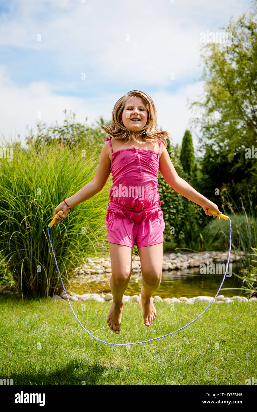 Active child - happy girl jumping with skipping rope outdoor, copy ...