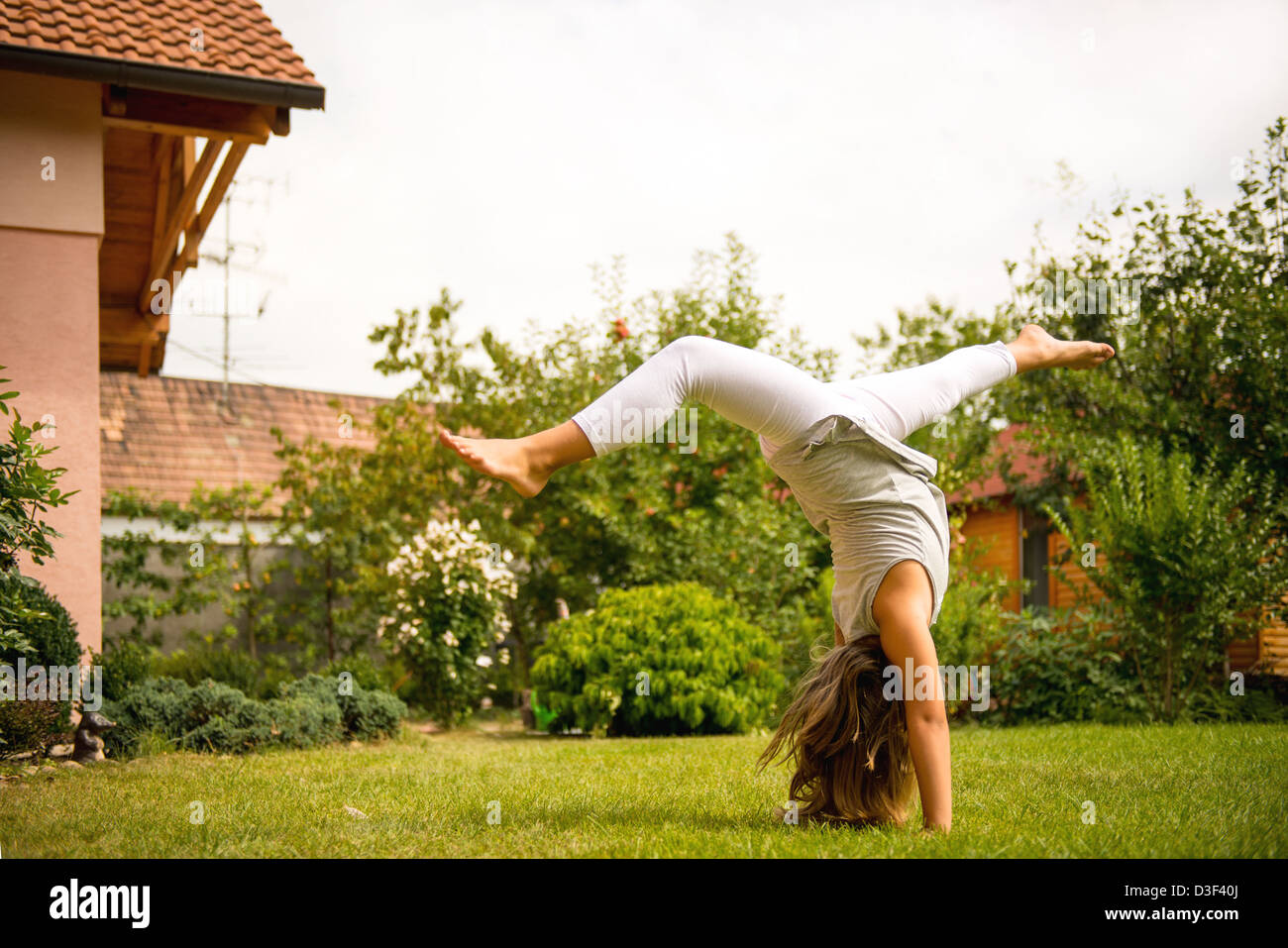Active childhood - little child making handstand outside in backyard ...