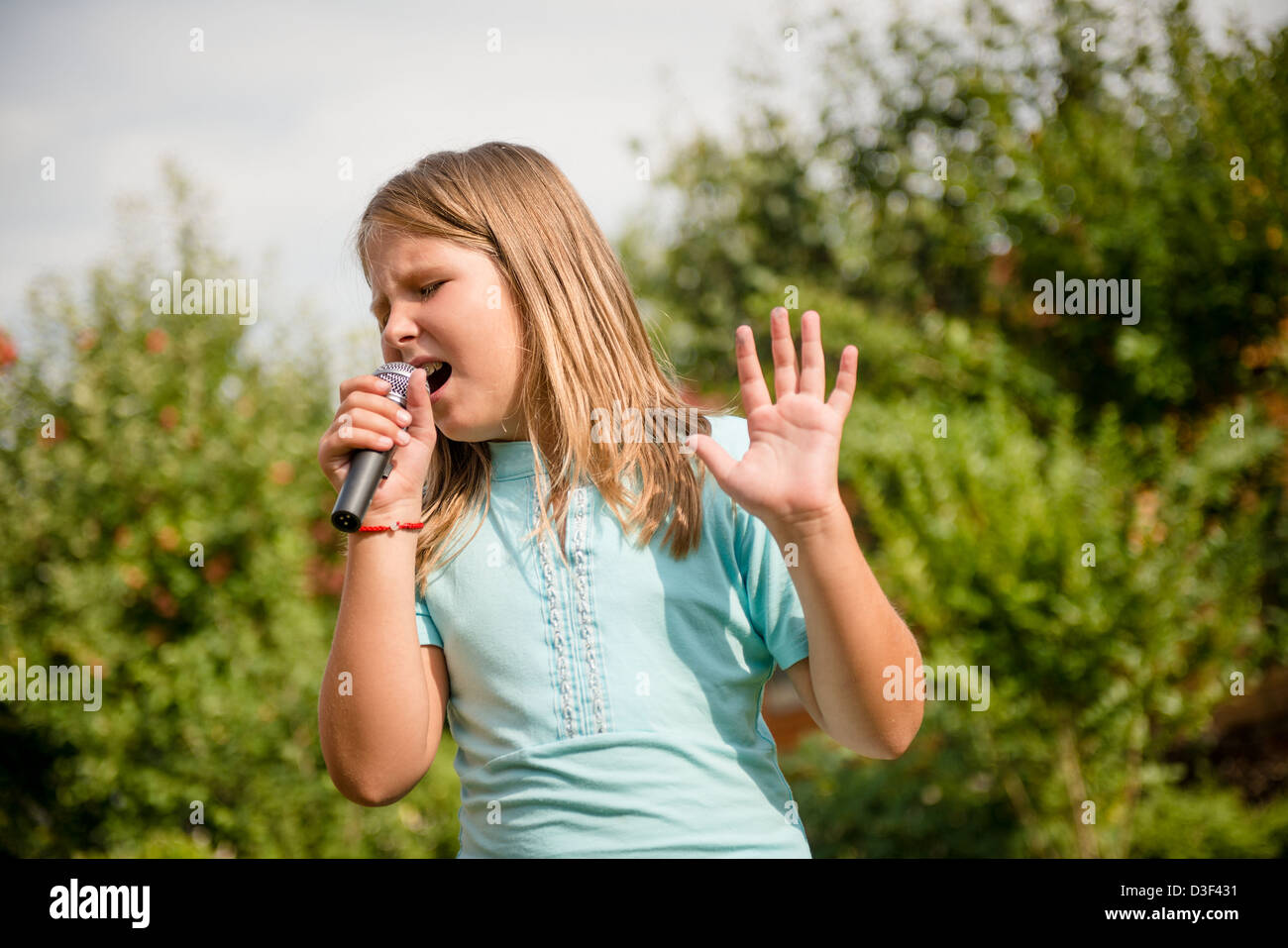 Happy childhood - child singing with microphone outdoor in backyard ...