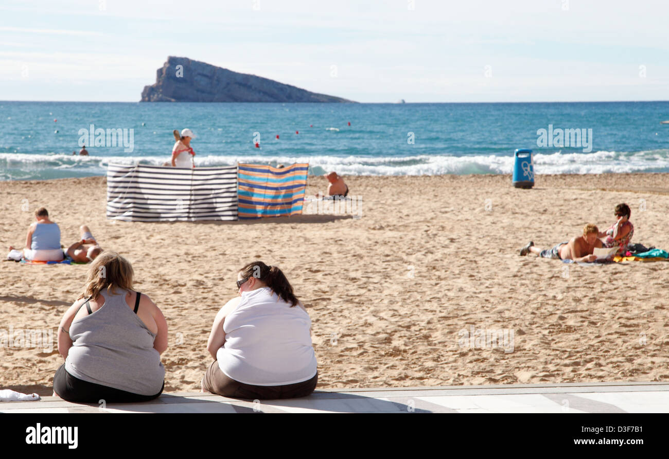 Two overweight obese fat young ladies sitting on the beach promenade in ...