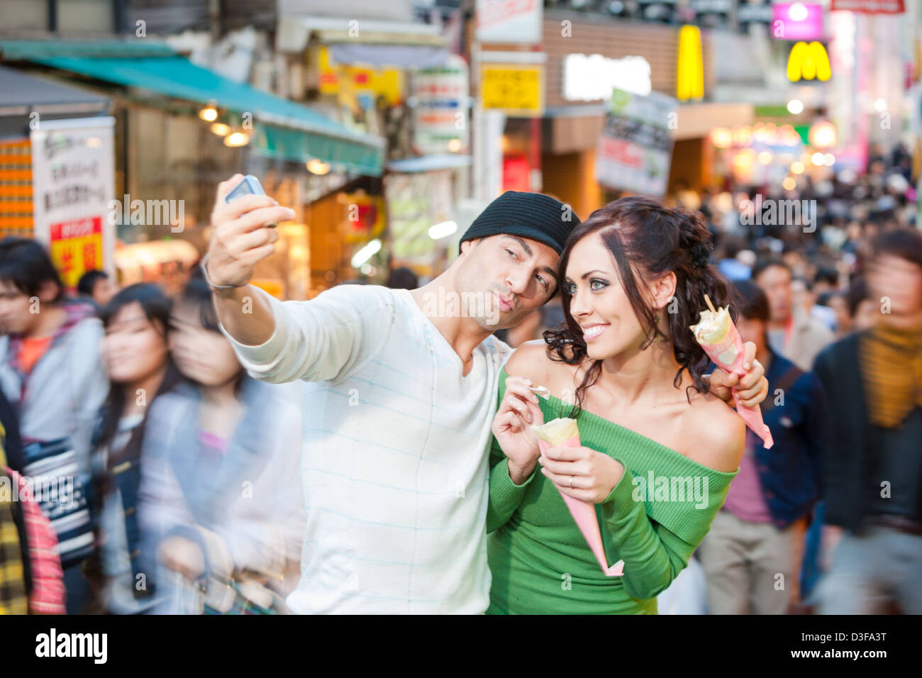 Playful couple takes a self portrait while eating crepes in downtown ...