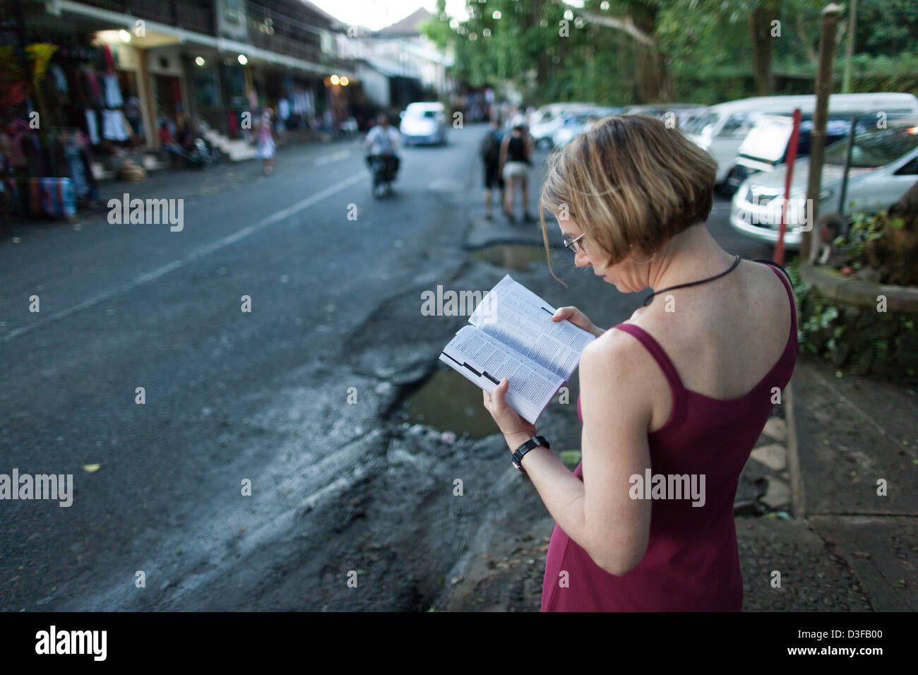 Tourist reading her guidebook on a street in Ubud, Bali, Indonesia ...