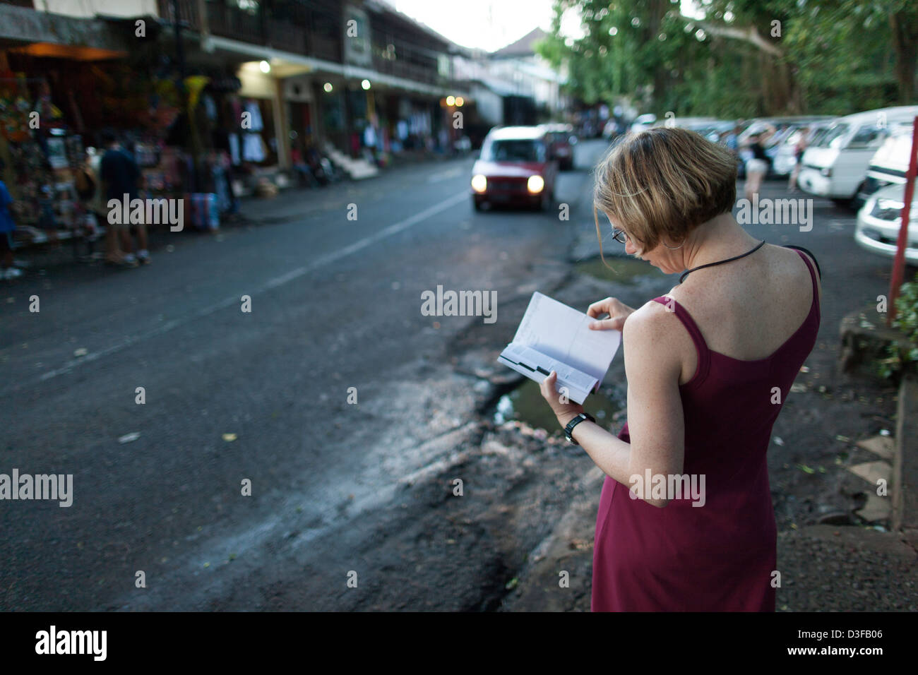 Tourist reading her guidebook on a street in Ubud, Bali, Indonesia ...