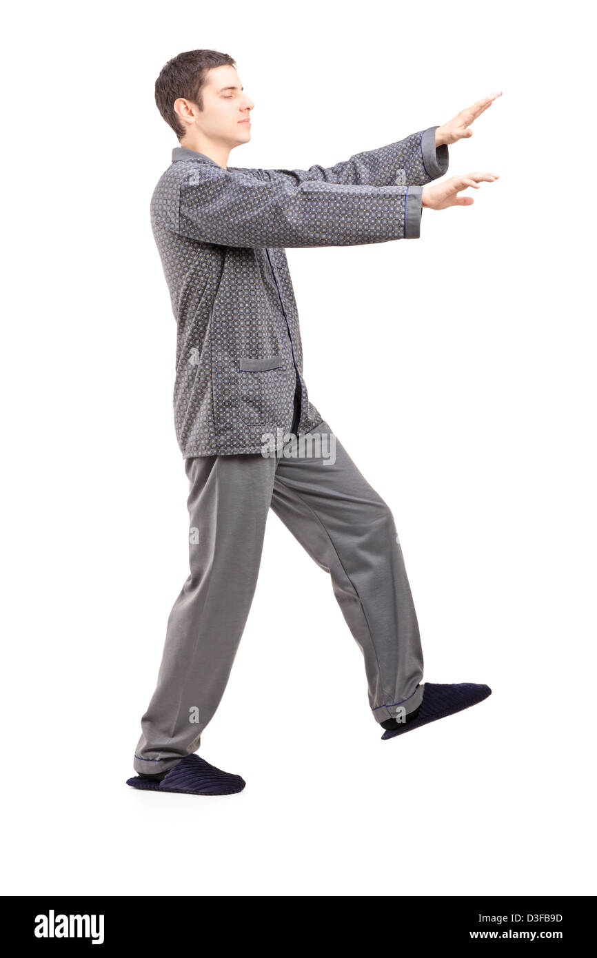 Full length portrait of a young man in pajamas sleepwalking isolated on ...
