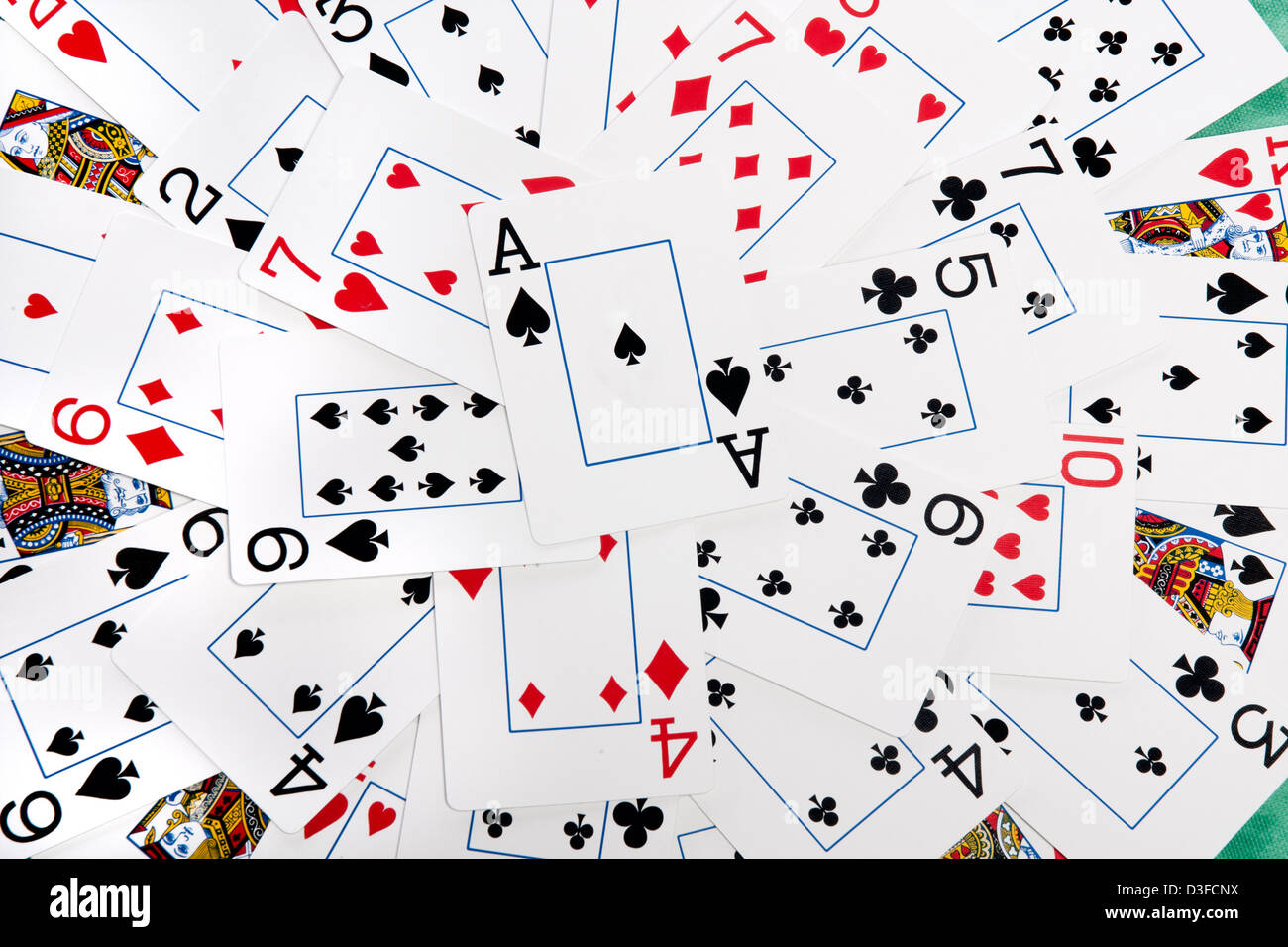 Close up view of a bunch of playing cards spread on a green cloth table ...