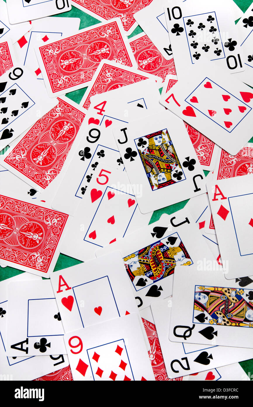 Close up view of a bunch of playing cards spread on a green cloth table ...