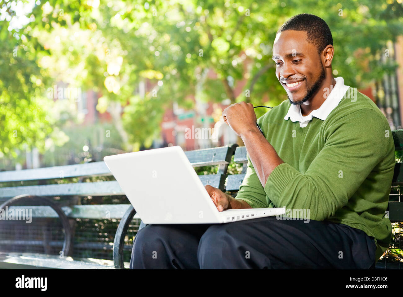 Black American in a neighborhood park using the convenience of wifi for ...