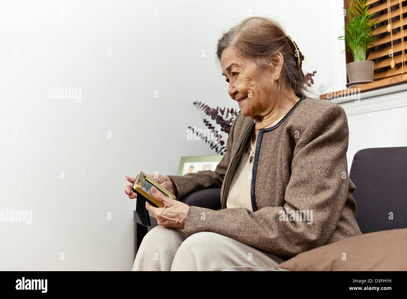 A female senior citizen of 80 plus years is holding framed photo of ...
