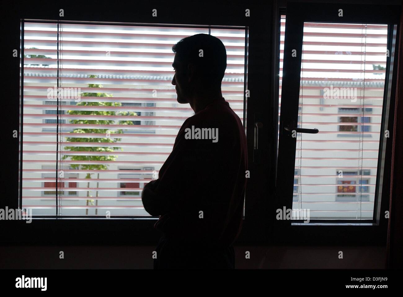 (dpa) - The silhouette of an asylum seeker is seen against the window ...