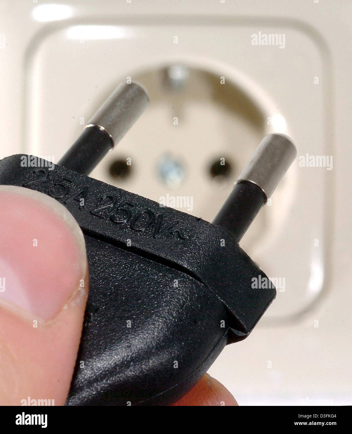 (dpa) - A man puts a plug featuring the inscription 250 volts into a ...