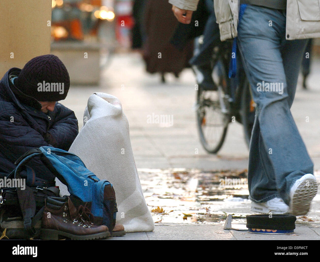 (dpa) - A homeless man sits on a sidewalk begging for change in Berlin ...