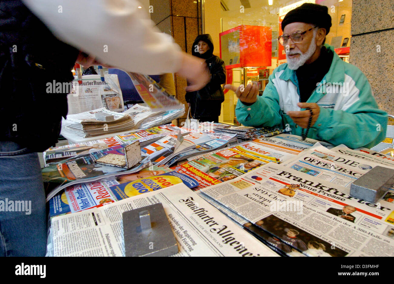 (dpa) - A newspaper salesman handles change at his newsstand in front ...