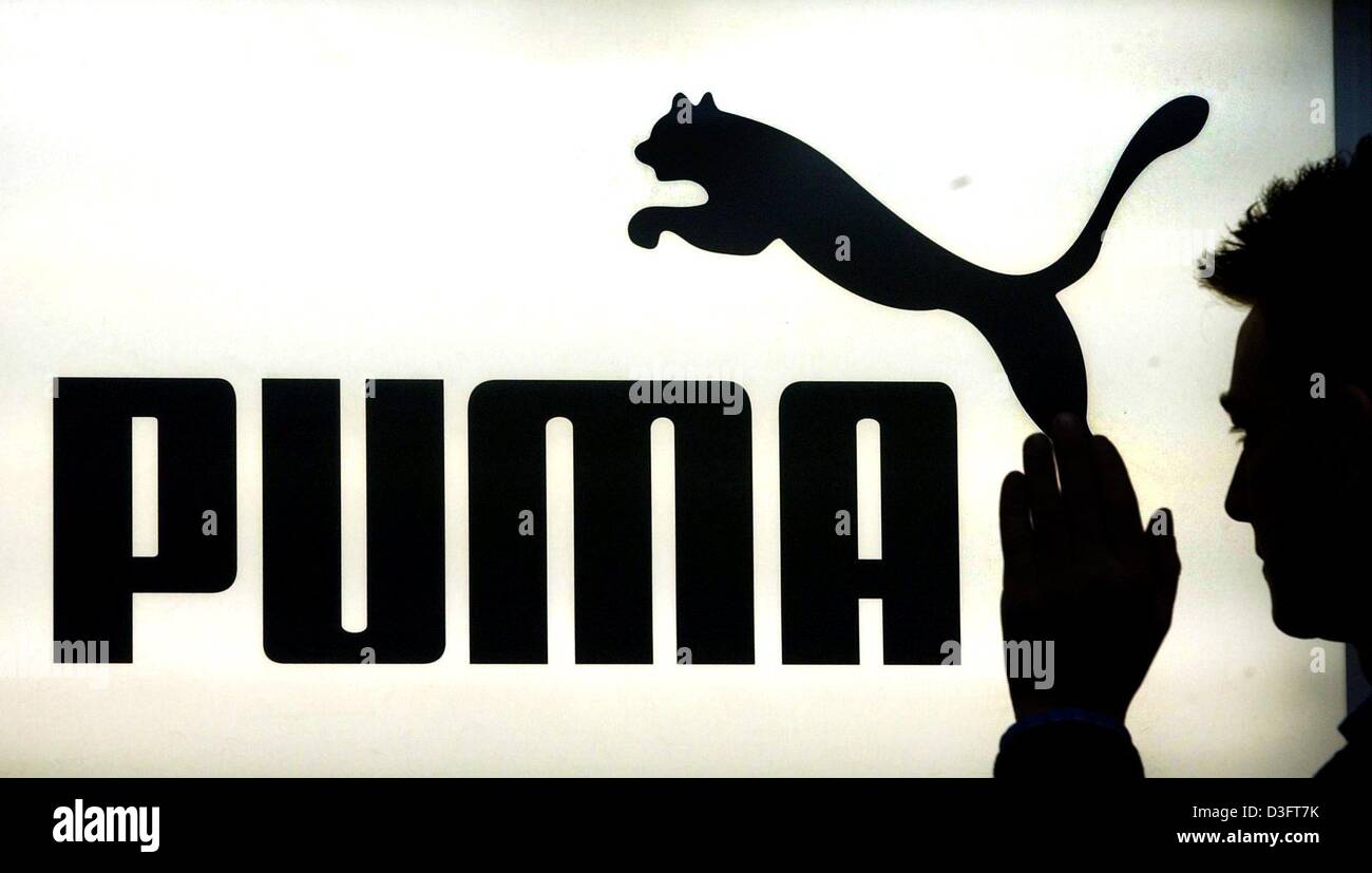 (dpa) - A man places his hand on an illuminated logo of sporting goods ...