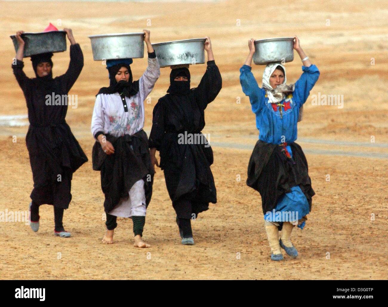 (dpa) - A group of Iraqi women walk together and carry tin buckets on ...