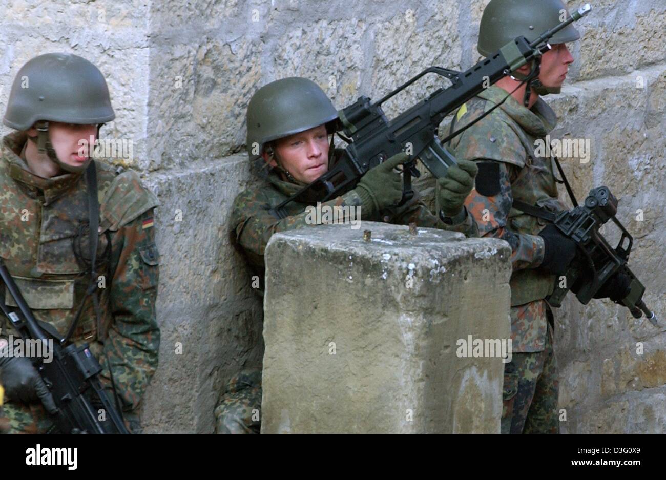 (dpa) - Soldiers of the German army take cover along a wall during a ...