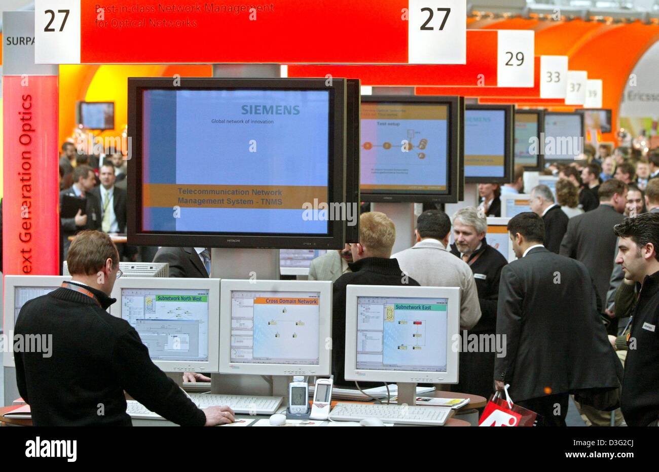 (dpa) - Visitors stand in front of computer terminals and large ...