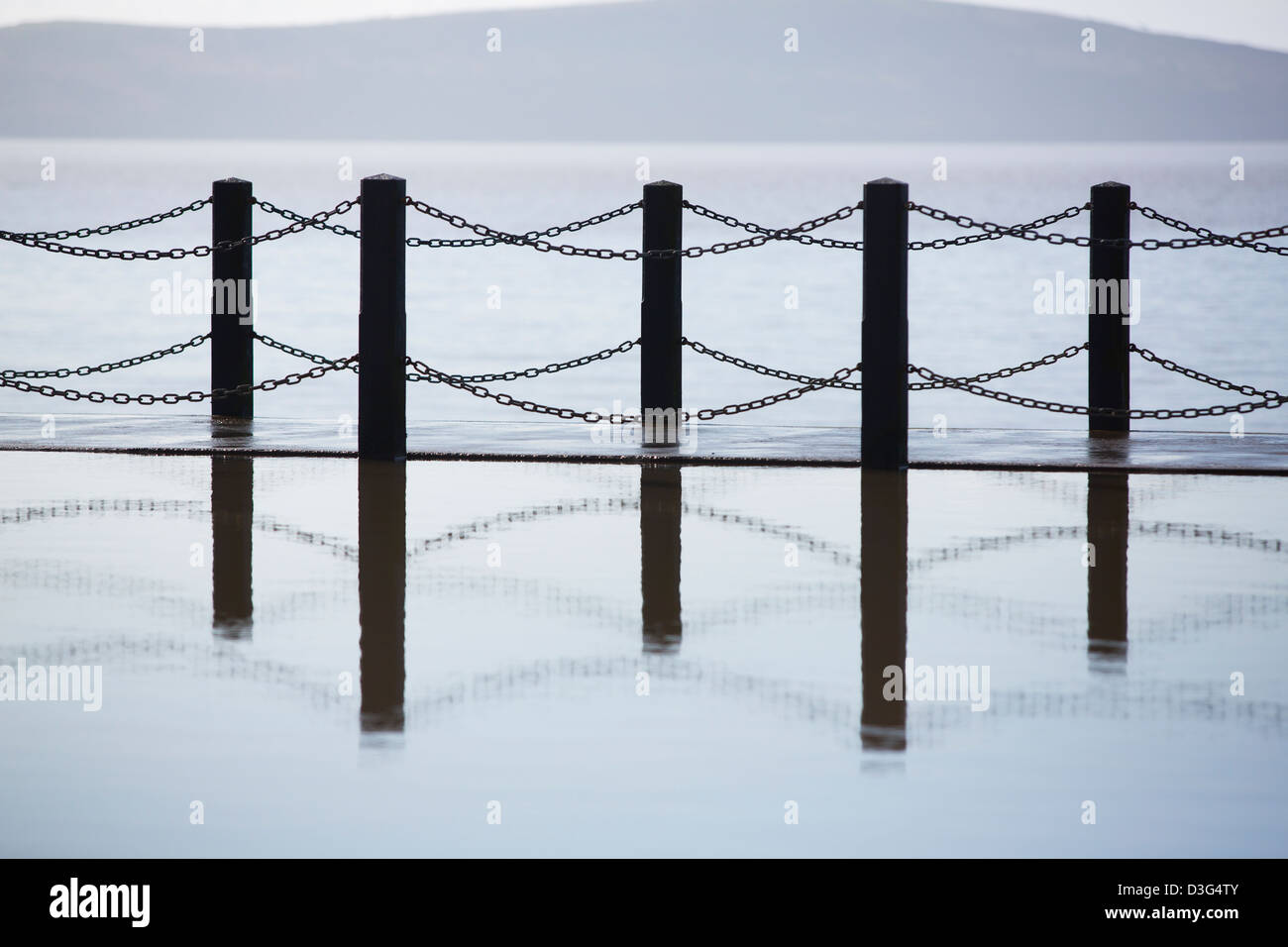 Fence reflected in a pool of water with the sea in the background Stock ...