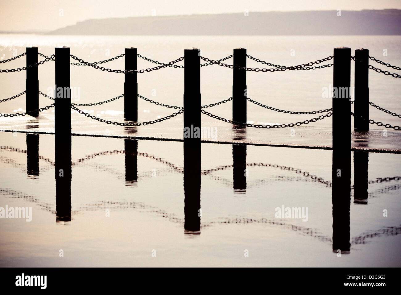 Fence reflected in a pool of water with the sea in the background post ...