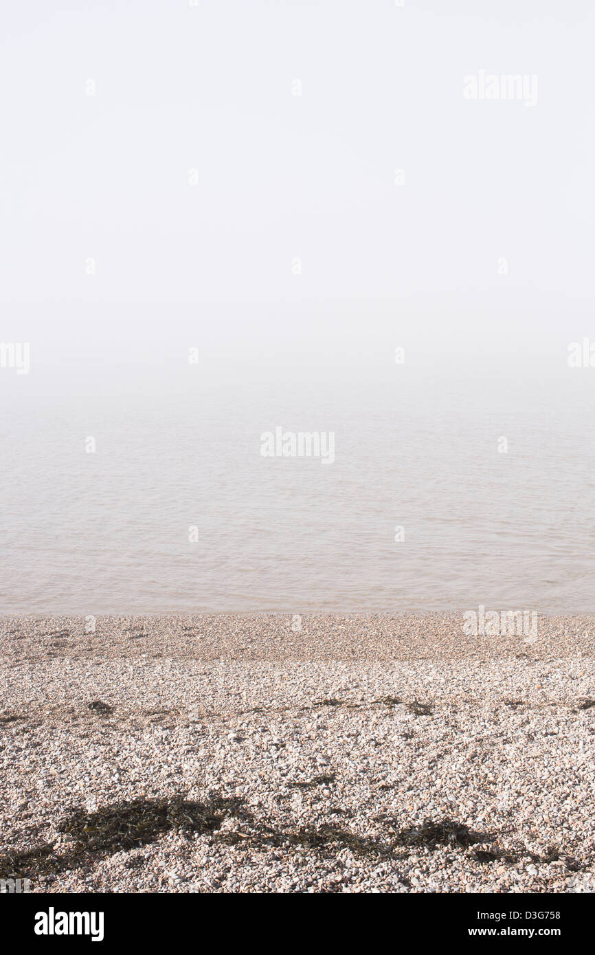Pebble stone beach with waves lapping and the sea obscured by ocean ...