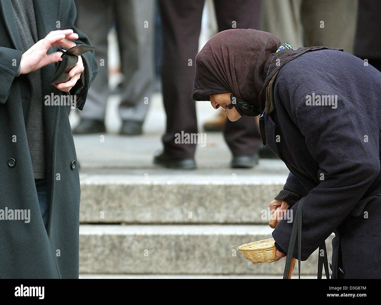 (dpa) - A beggar woman begs for a donation while a pedestrian takes ...