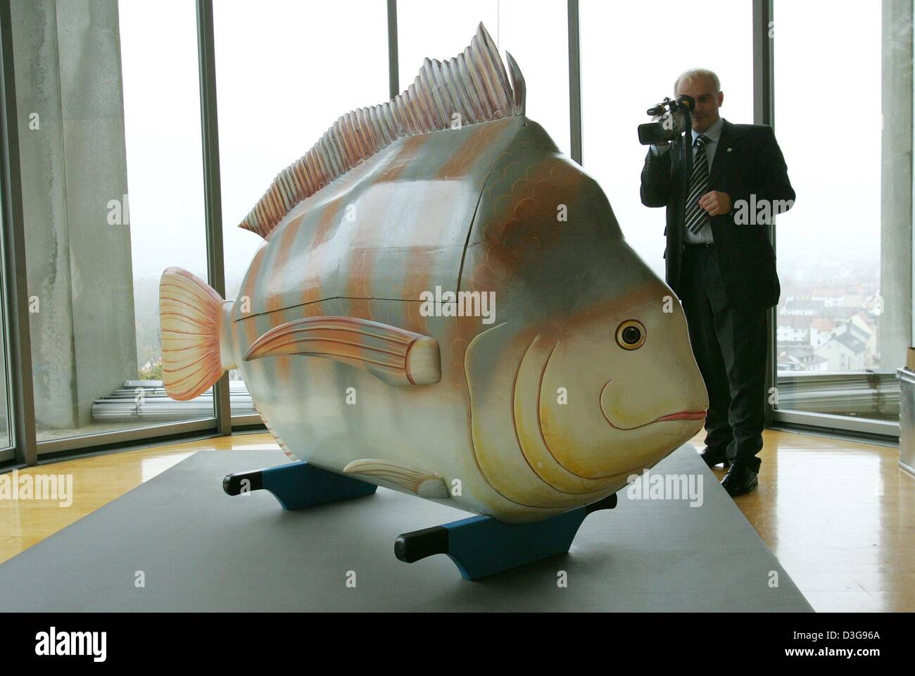(dpa) - A man films a fish-shaped coffin from Ghana on display at the ...