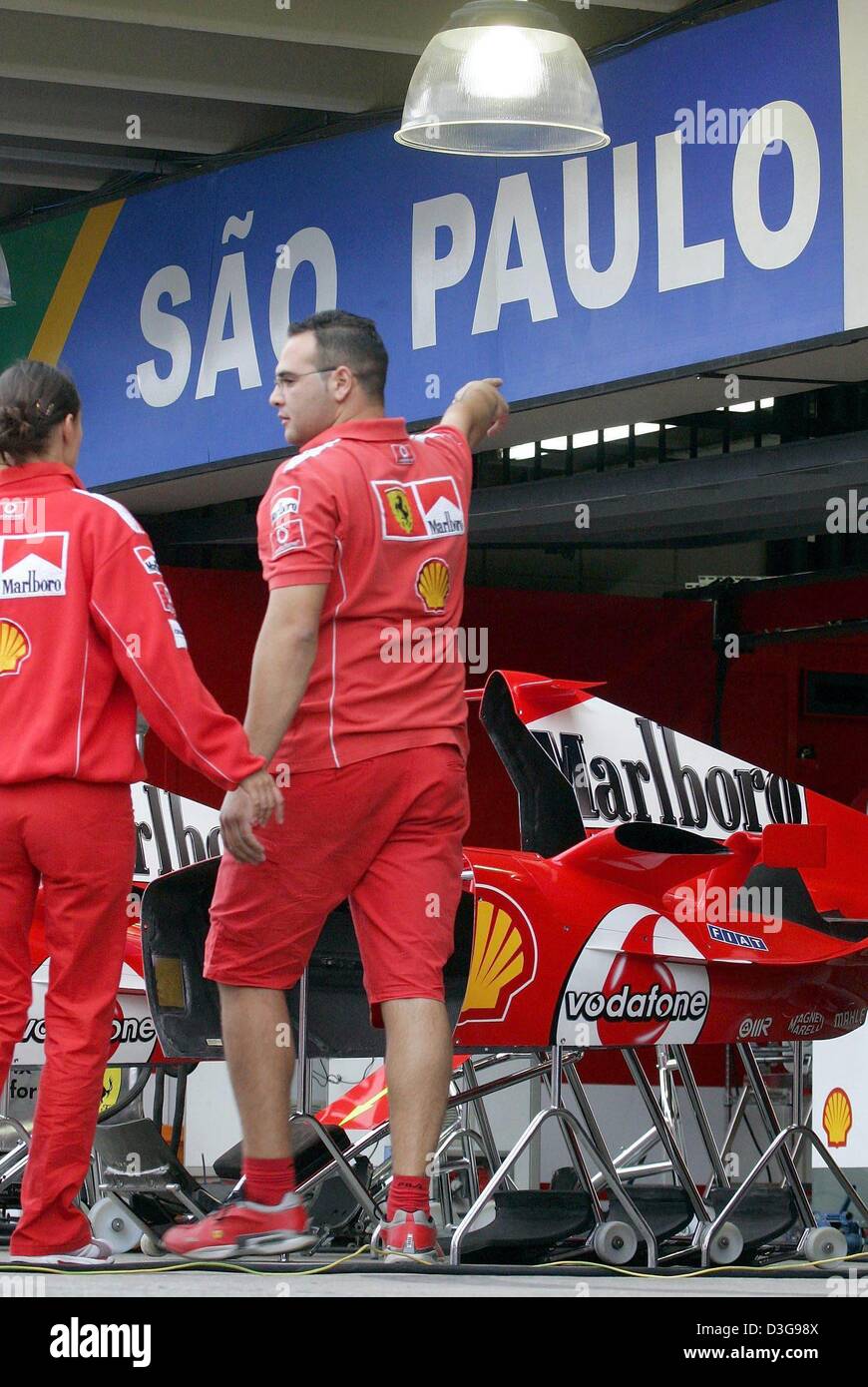 (dpa) - Ferrari Formula One mechanics walk through the pits at the ...