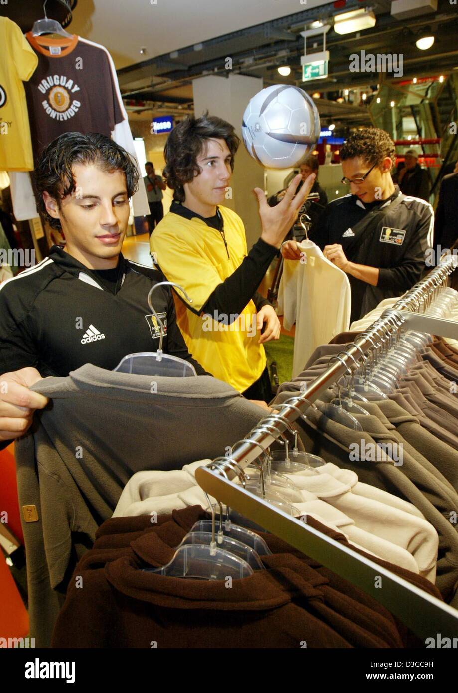 (dpa) - Three young soccer fans inspect the goods on sale at an ...