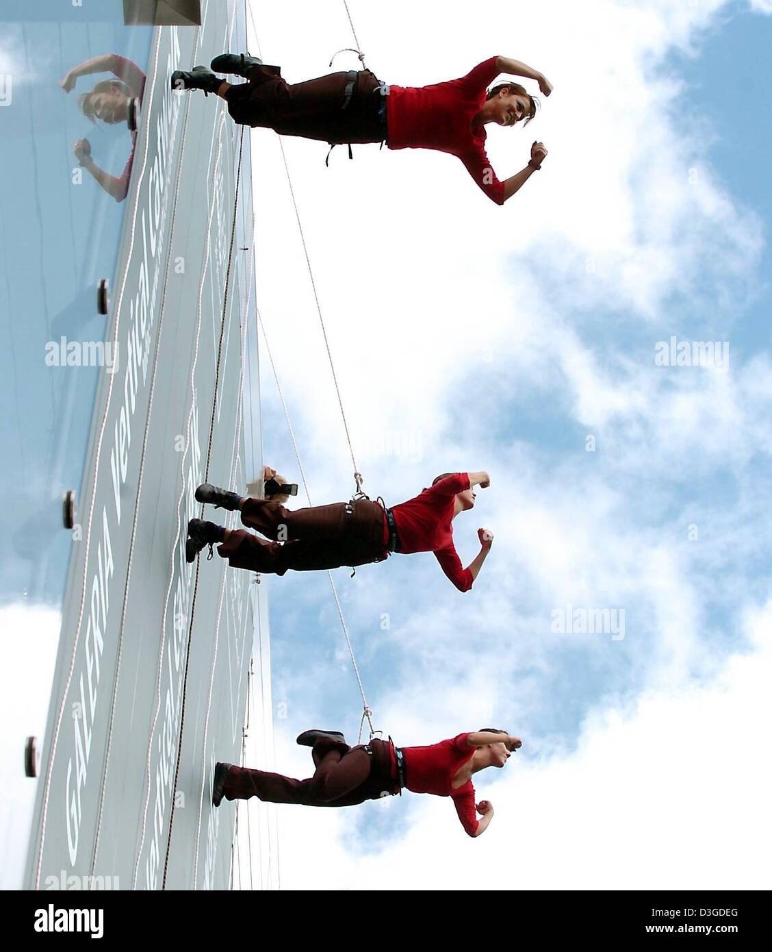 (dpa) - Fashion models secured by ropes walk down a vertical catwalk on ...