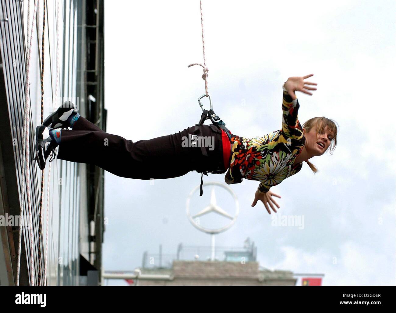 (dpa) - A fashion model secured by a rope walks down a vertical catwalk ...