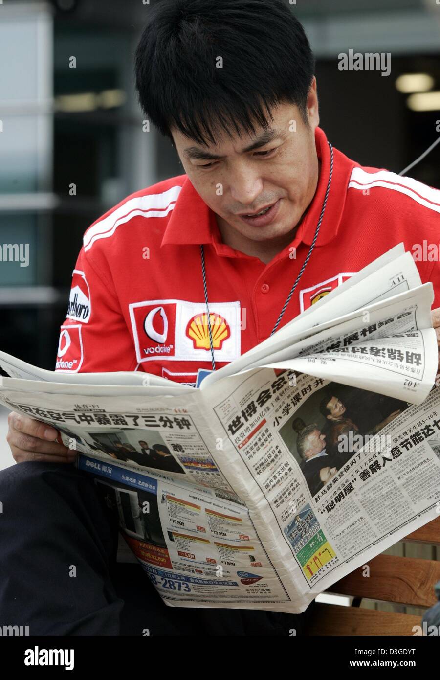 (dpa) - A Chinese Ferrari employee reads a newspaper in the paddock at ...