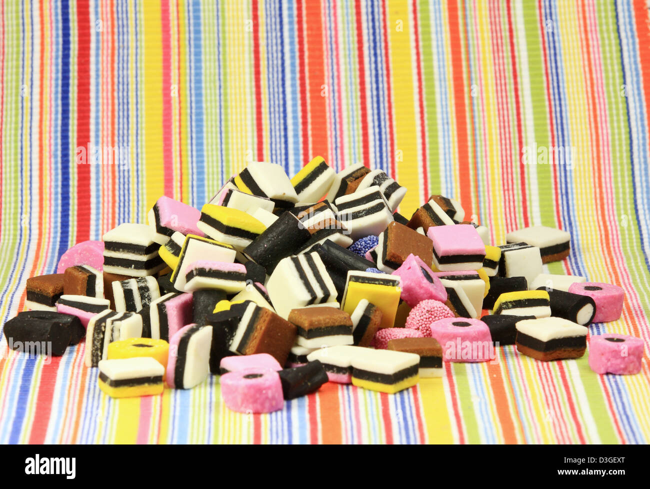 A pile of colourful liquorice sweets against a colourful, stripey ...