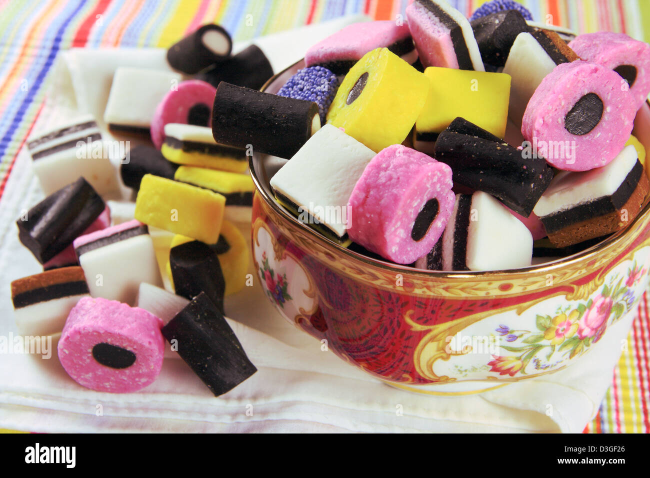 Liquorice sweets piled inside a colourful with loose sweets outside on ...