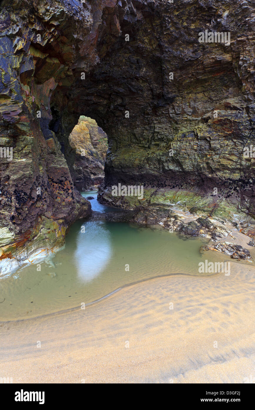 An archway through the cliff at Perranporth beach in Cornwall England ...