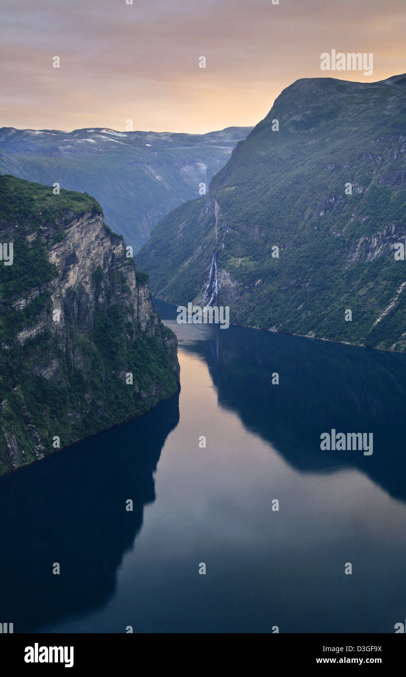 Massive, tall cliffs and waterfalls at sunset in the famous Geiranger ...