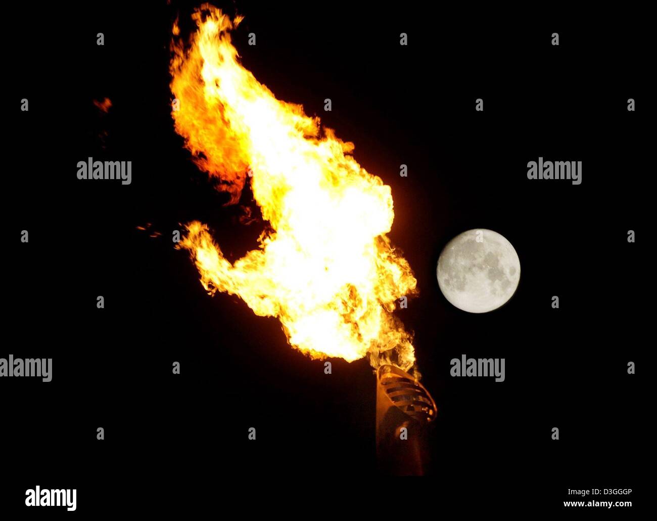 (dpa) - An almost full moon is seen behind the Olympic Flame that burns ...