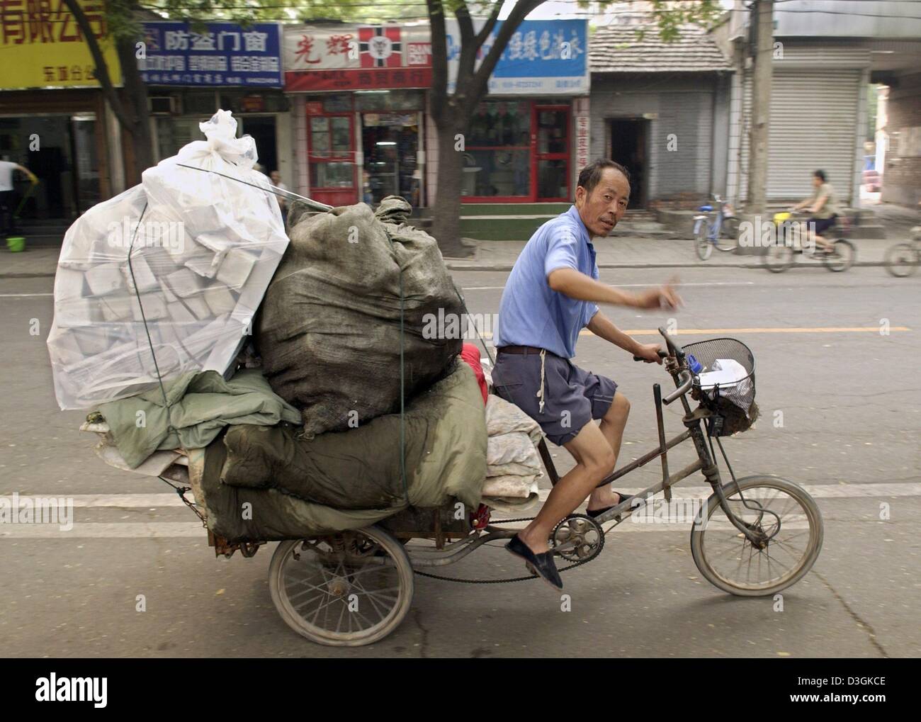 (dpa) - A man rides with his heavy loaded tricycle along a road in the ...