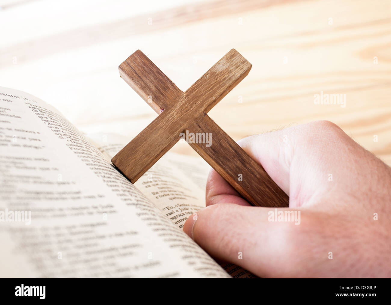 man holding the cross in the hand ,with bible under Stock Photo - Alamy